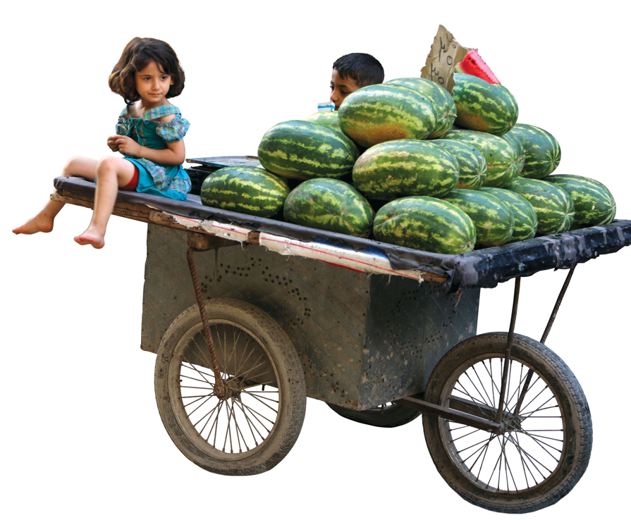 A girl rests on a watermelon cart inside a market on the last week of ...